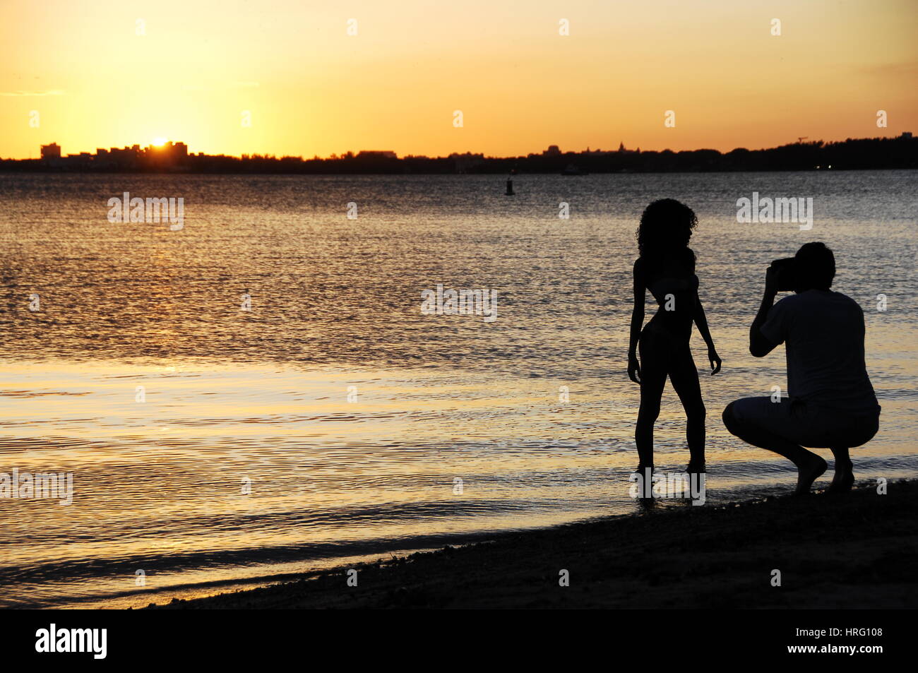 photographer takes pictures of a model at sunset on the sea Miami ...