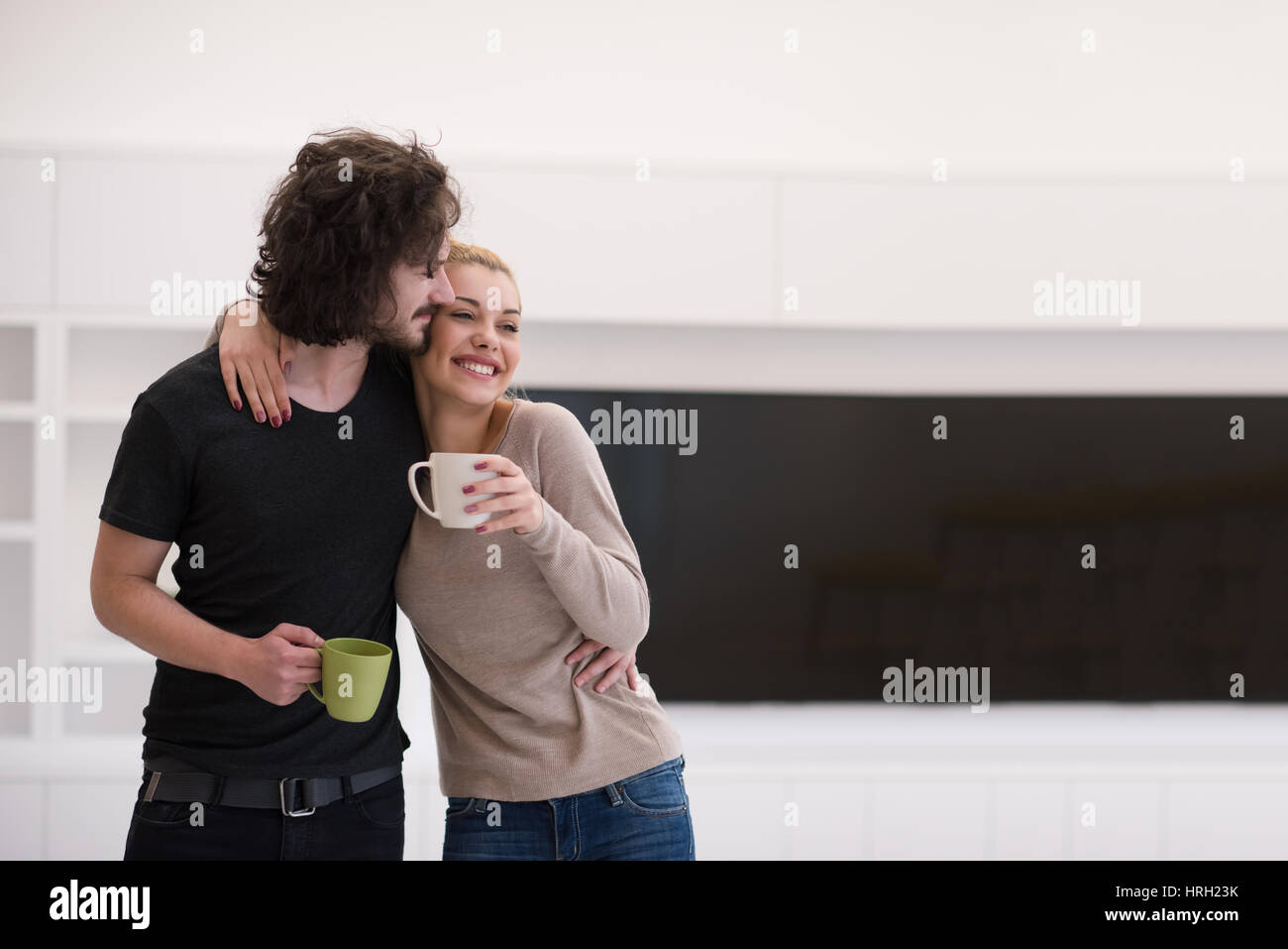 Portrait of a happy young beautiful couple hugging and drinking coffee ...