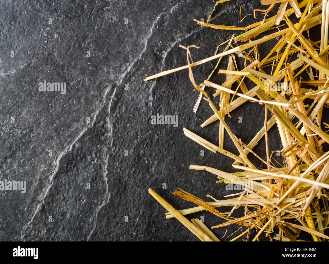A bunch of yellow straw on the black background of an empty slab of ...