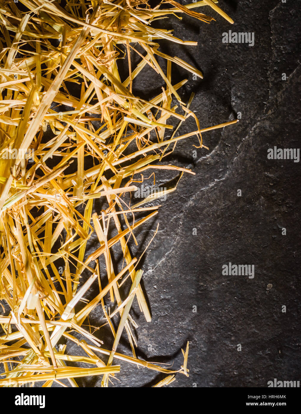 A bunch of yellow straw on the black background of an empty slab of ...