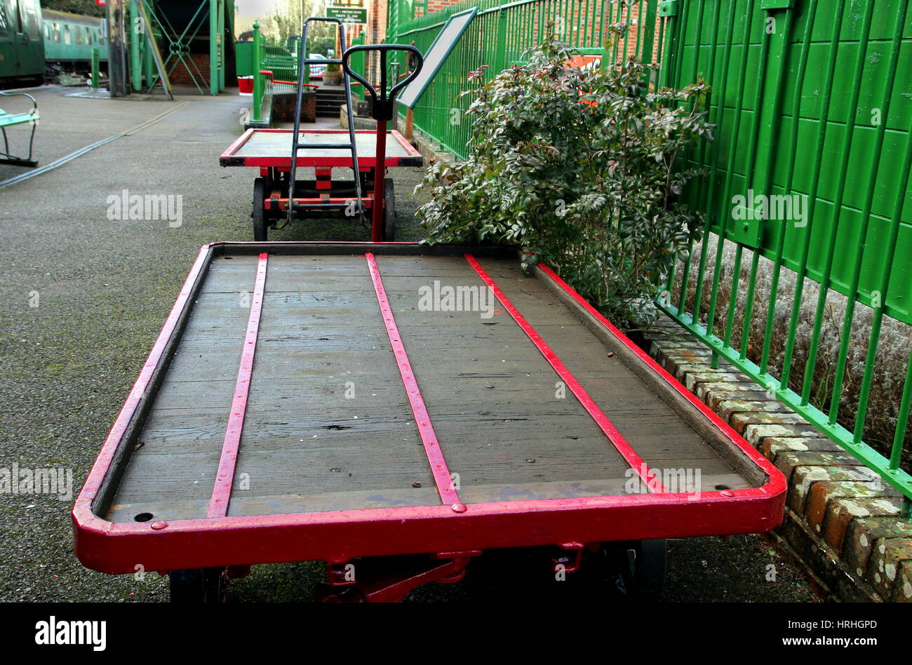 Vintage retro red railway luggage trolley on an old green painted ...