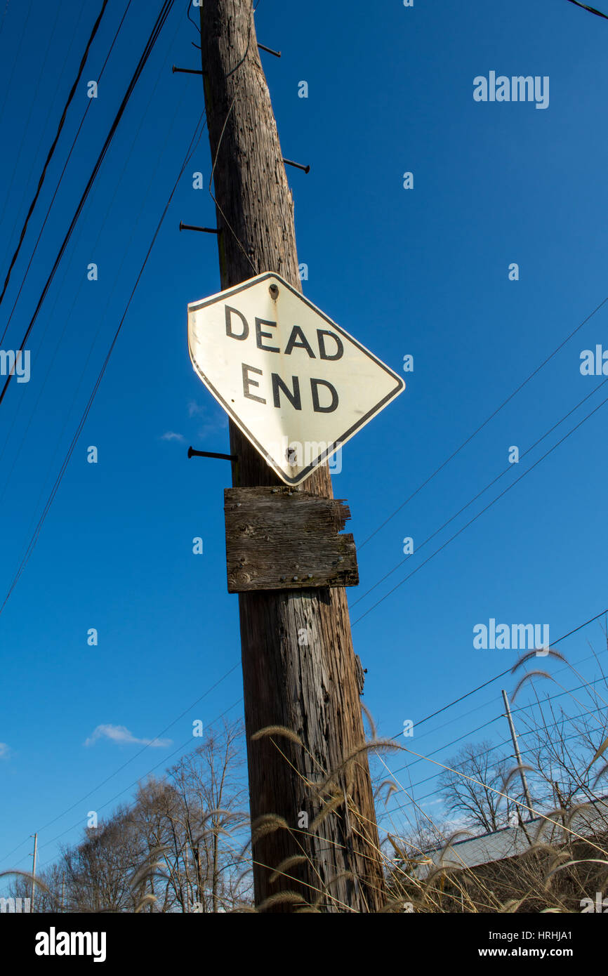 Old dead end road sign on wooden telegraph pole, blue sky behind Stock ...