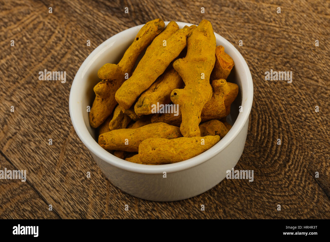 Tumeric roots heap in the bowl over wooden background Stock Photo - Alamy