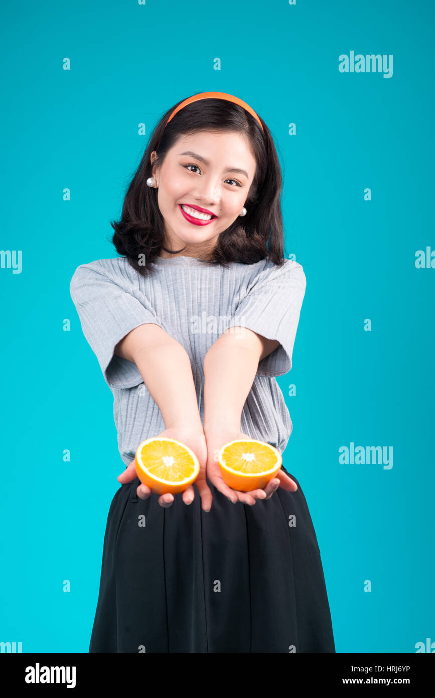 Healthy food. Smiling lovely pinup asian girl holding orange over blue ...