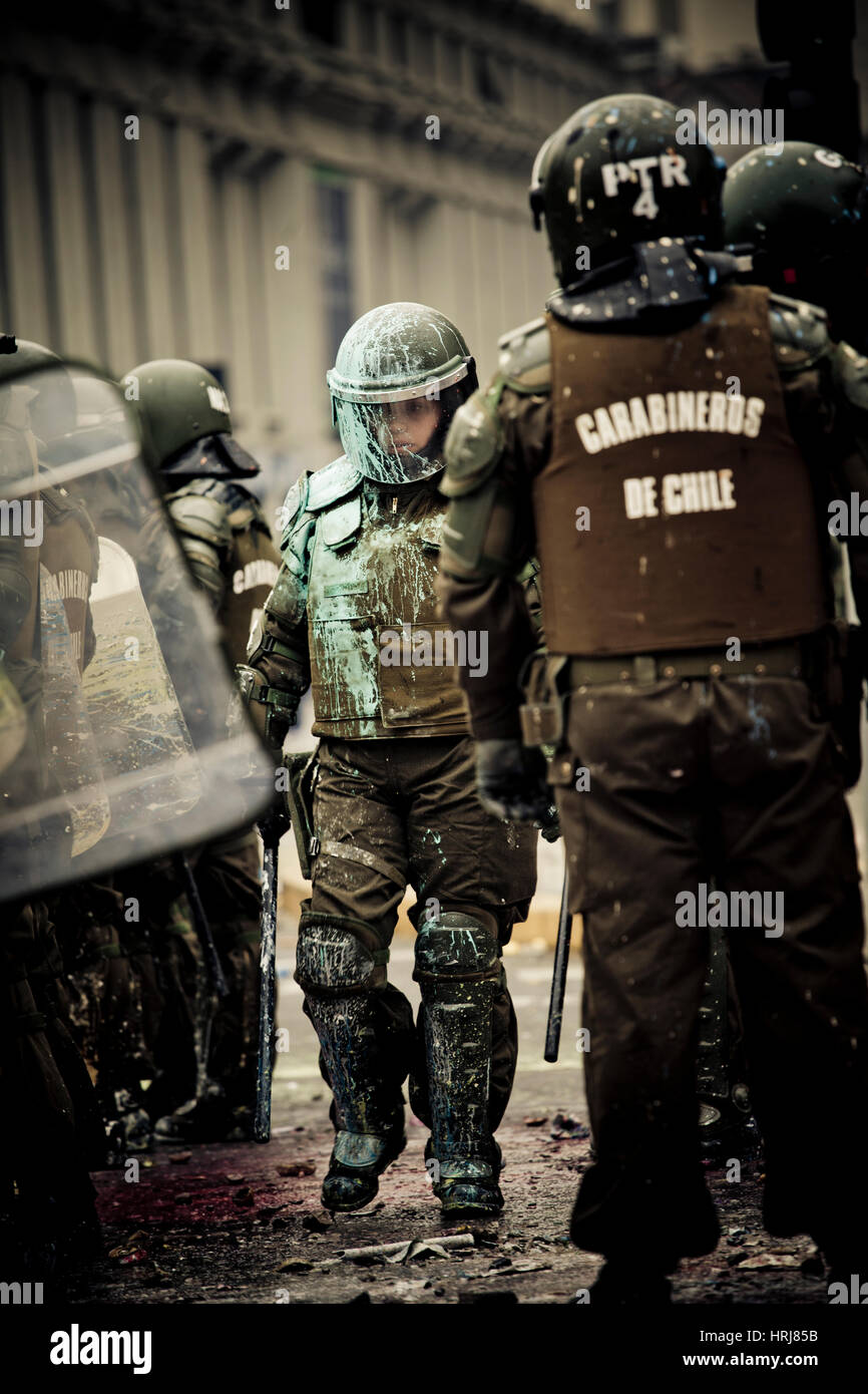 A riot police woman is hit by a bottle with paint, during a ...