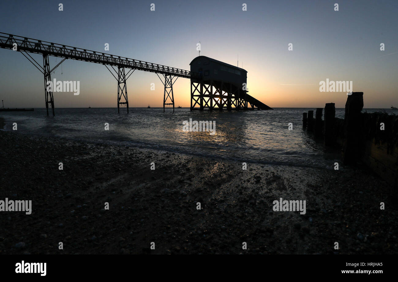 The sun rises behind the RNLI Lifeboat Station on the East beach in ...