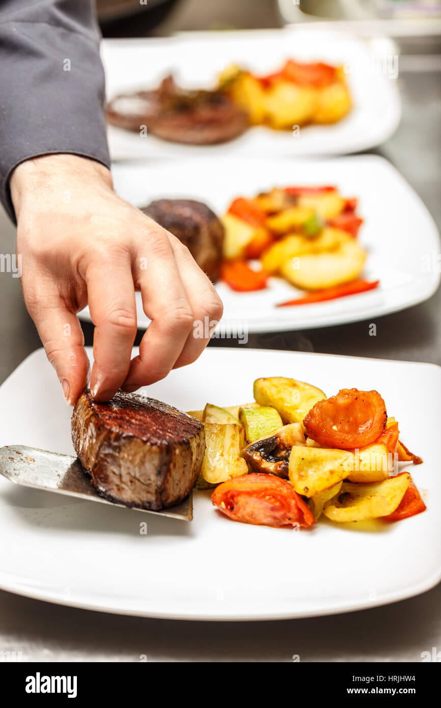 Chef making dinner dish on commercial kitchen Stock Photo - Alamy