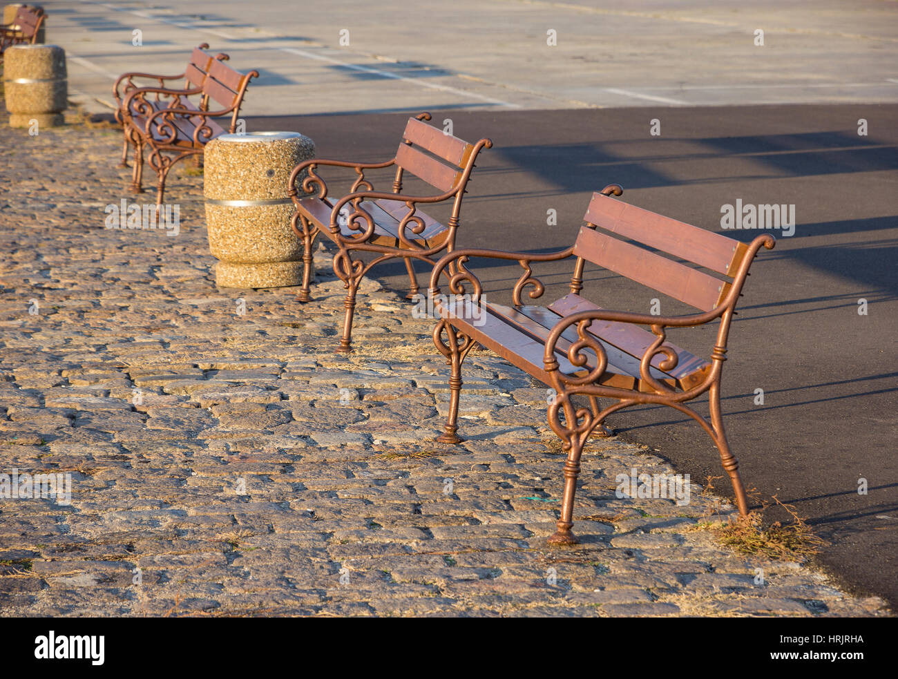 Empty wooden park benches with metal railing Stock Photo - Alamy
