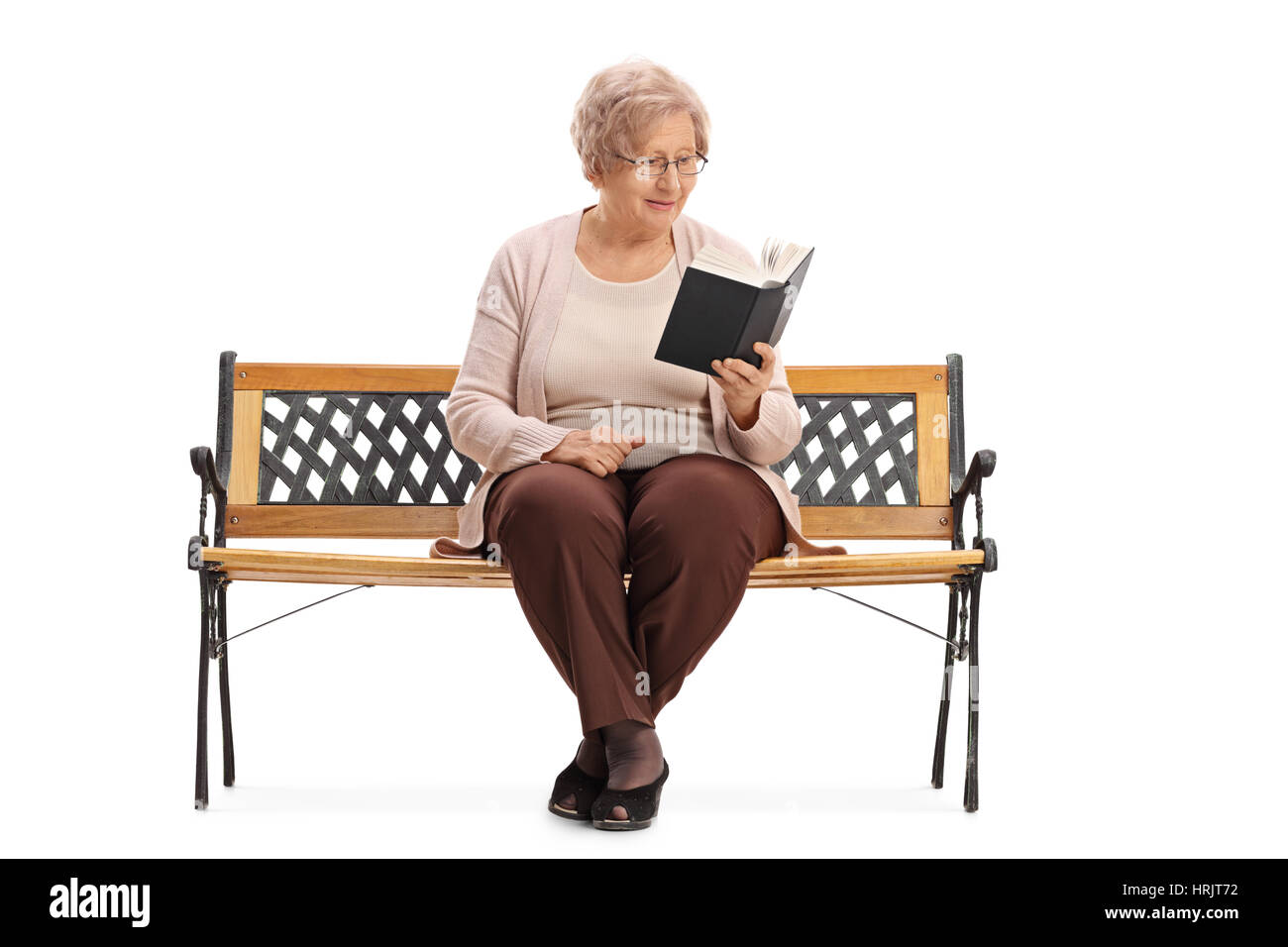 Senior sitting on a bench and reading a book isolated on white ...