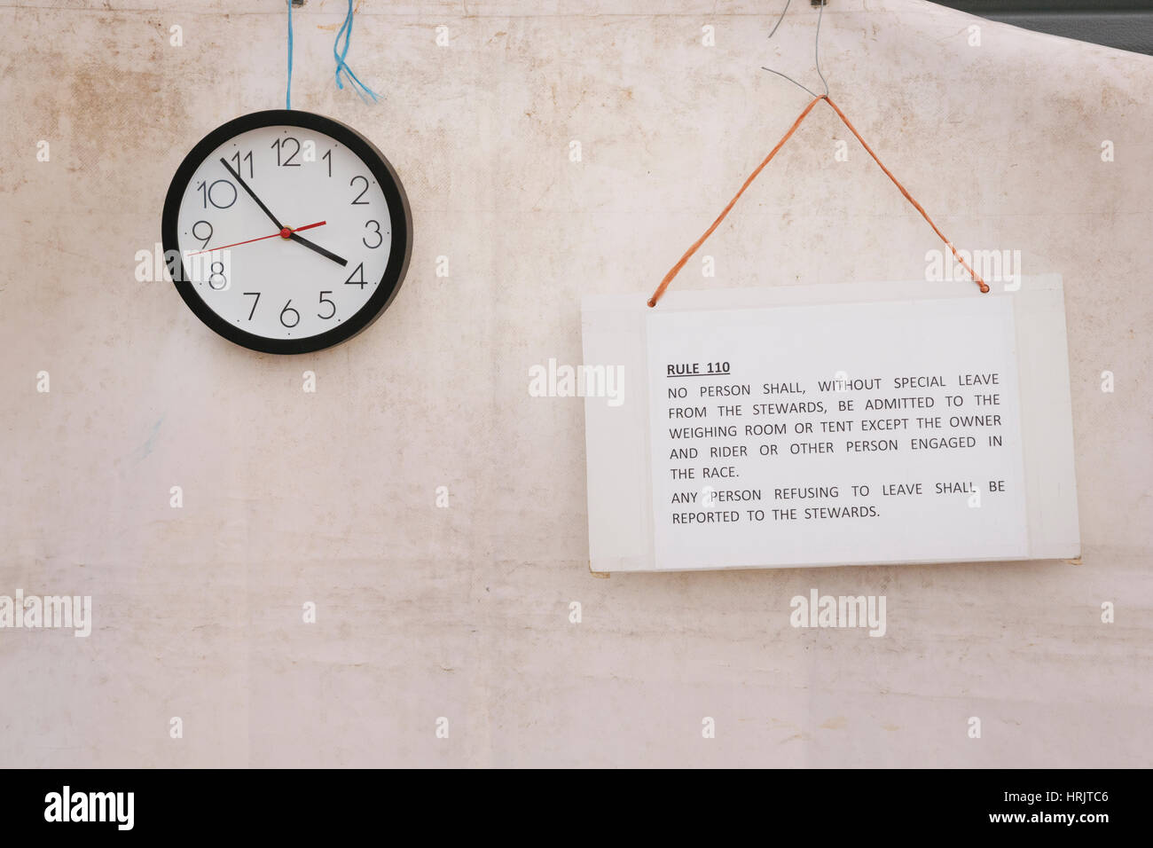 Clock and information sign on a wall in a weighing room for a horse ...