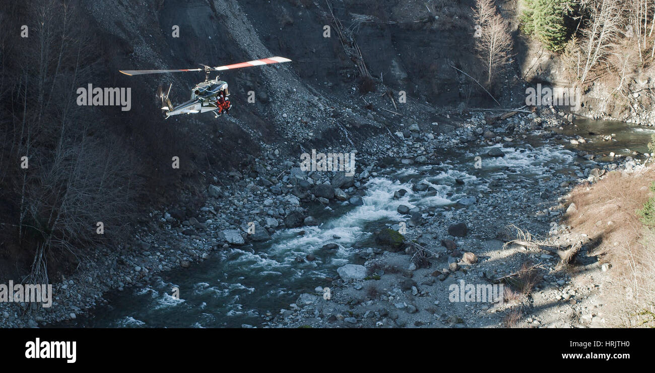 A helicopter flying above a rocky river bed in a valley Stock Photo - Alamy