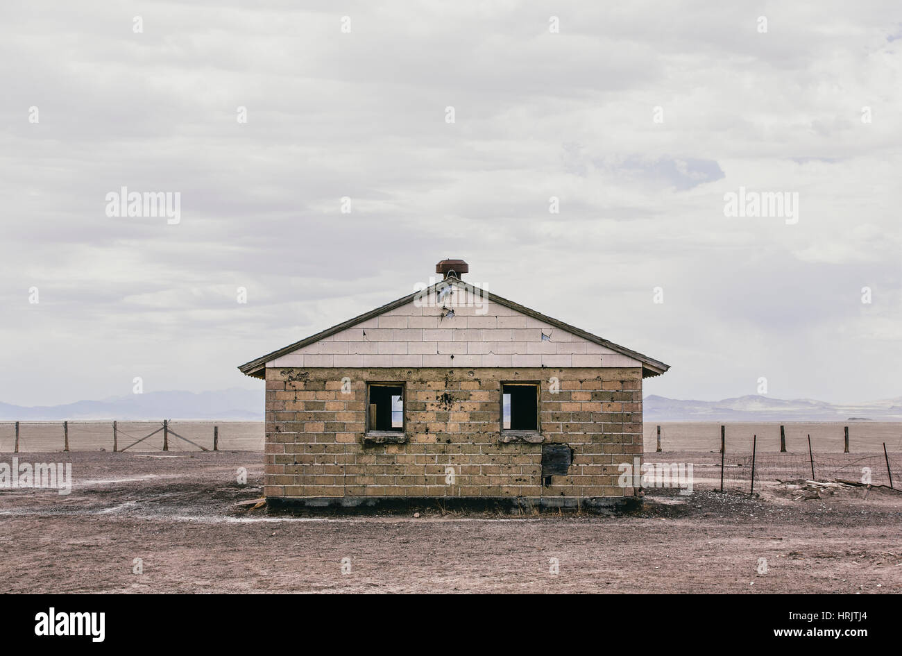 A derelict house in a flat landscape with mountains in the distance ...
