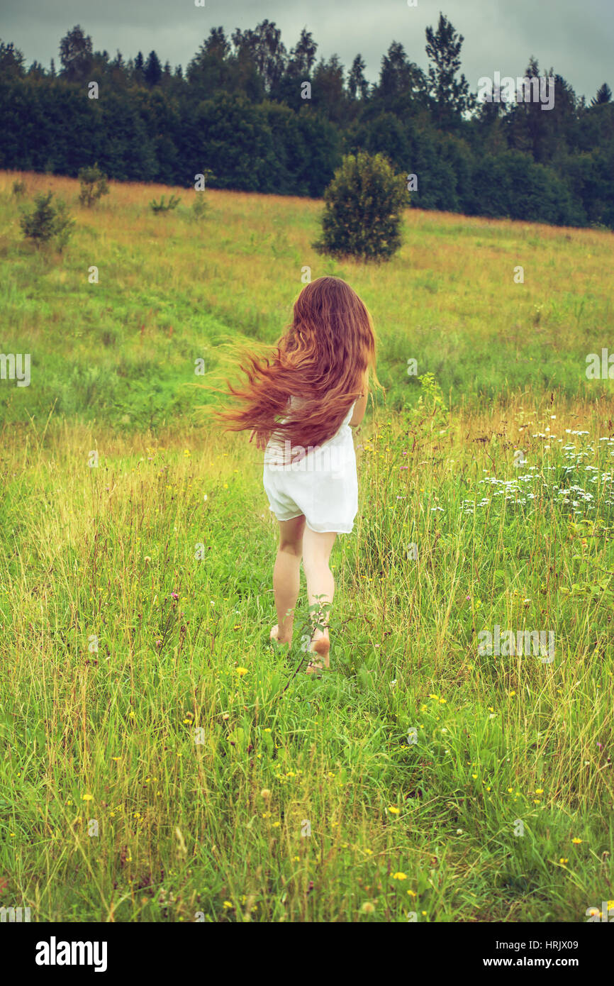 Beautiful girl with long hair running in a field Stock Photo - Alamy