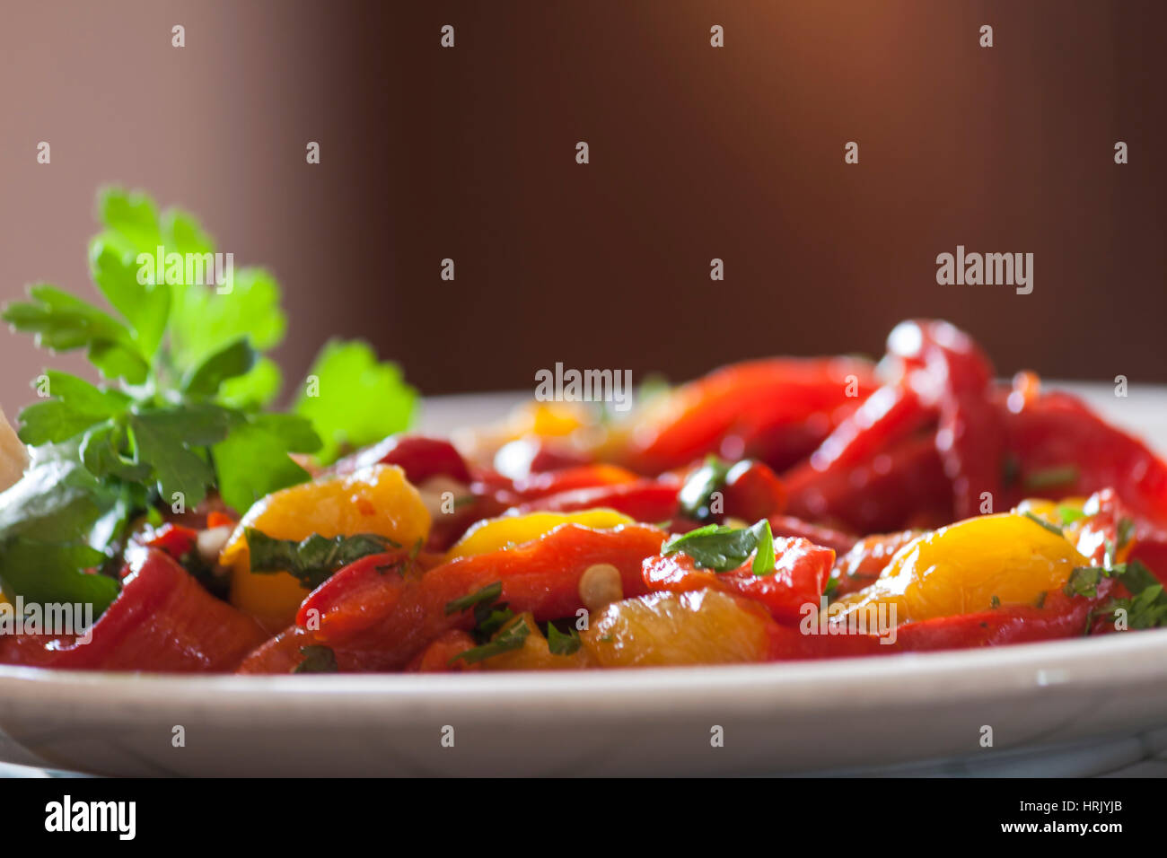 A dish of red and yellow peppers with green parsley Stock Photo - Alamy