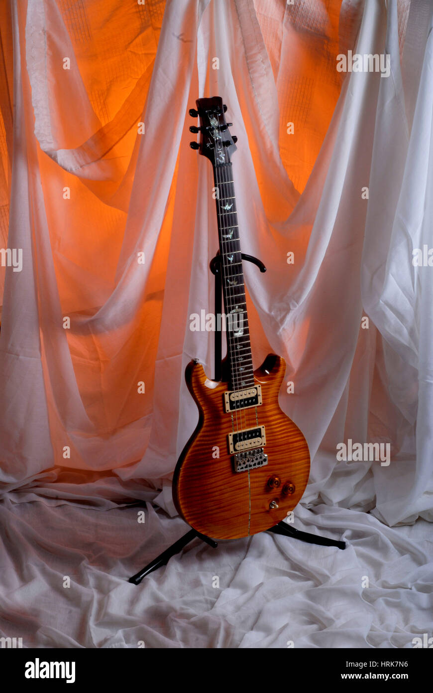 orange electric guitar with studio backdrop Stock Photo - Alamy