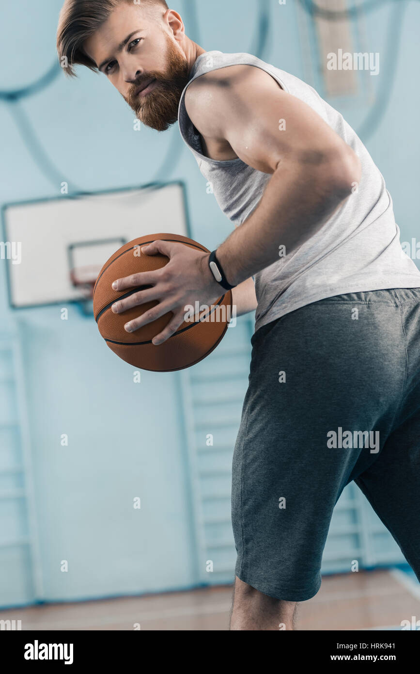 Bearded young basketball player holding ball and looking at camera ...