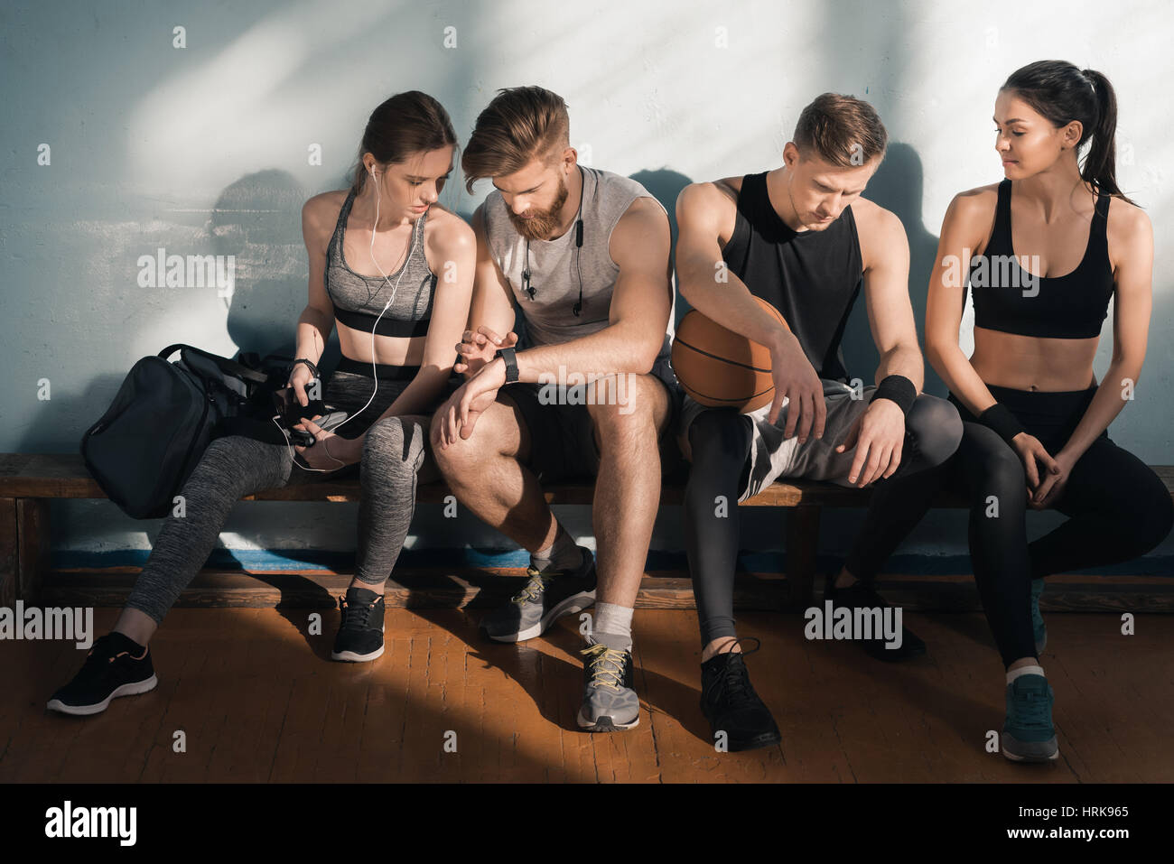 sporty men and women sitting on bench after training in gym Stock Photo ...