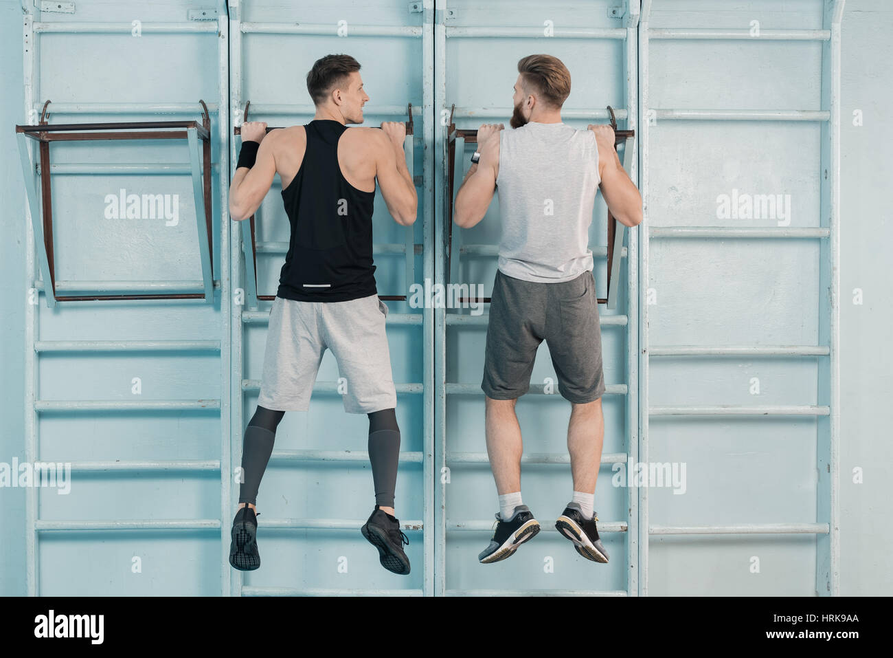 back view of sporty men exercising on sport equipment in gym Stock ...