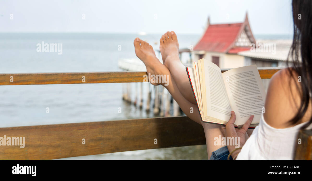 Girl reading a book on the balcony with seaside view Stock Photo - Alamy