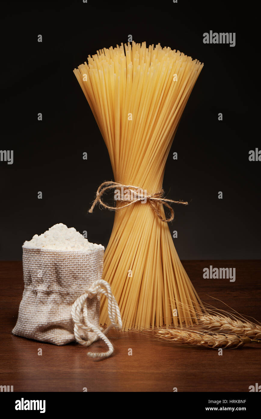 Dry spaghetti pasta tied up with rope, burlap bag of flour and wheat ...