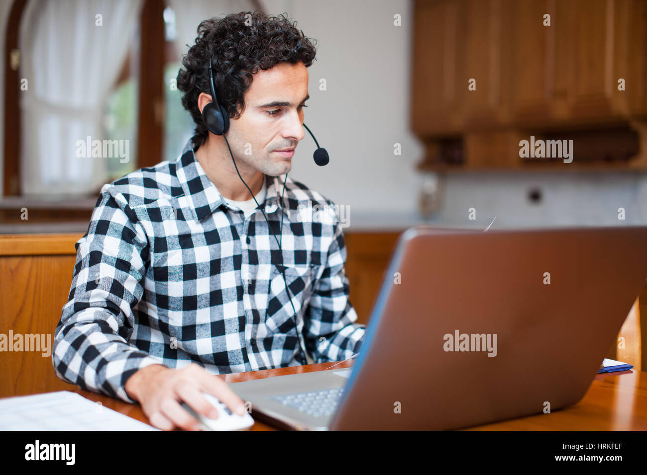 Guy using headset and laptop computer, chatting on Internet Stock Photo ...