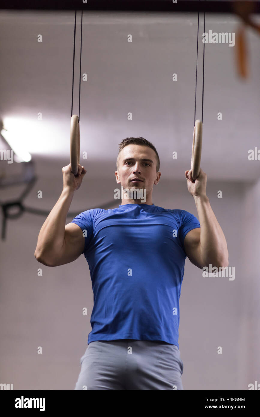 Fitness handsome man doing dipping exercise using rings in the gym ...