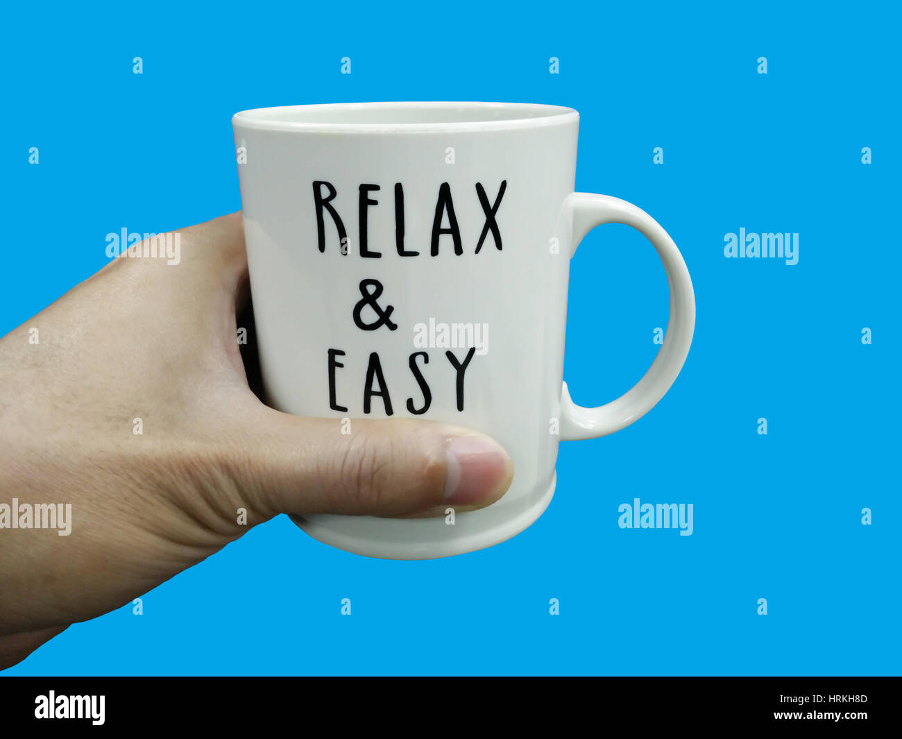 male hand holding a mug isolated on blue background Stock Photo - Alamy