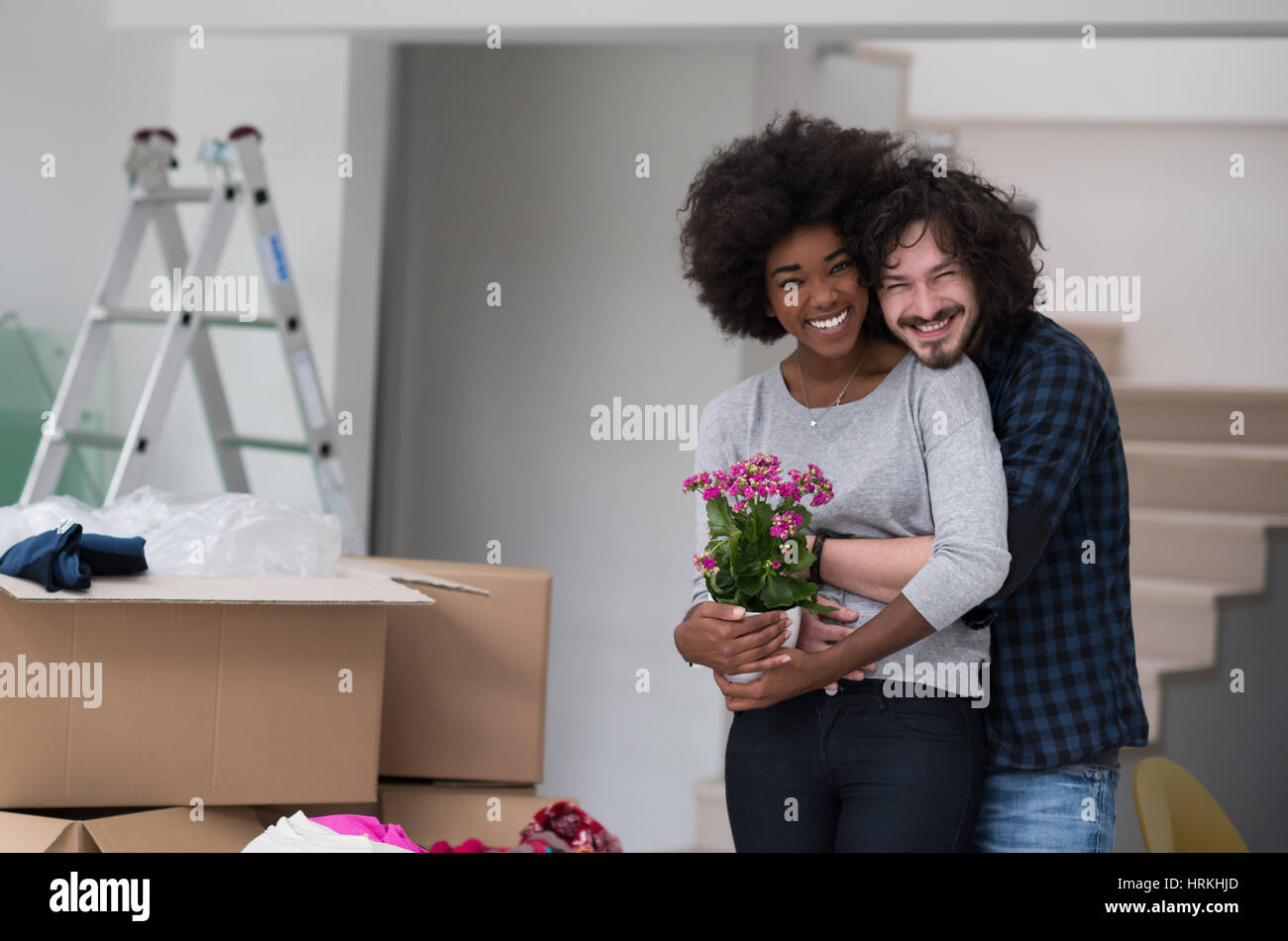 Happy young multiethnic couple unpacking or packing boxes and moving ...