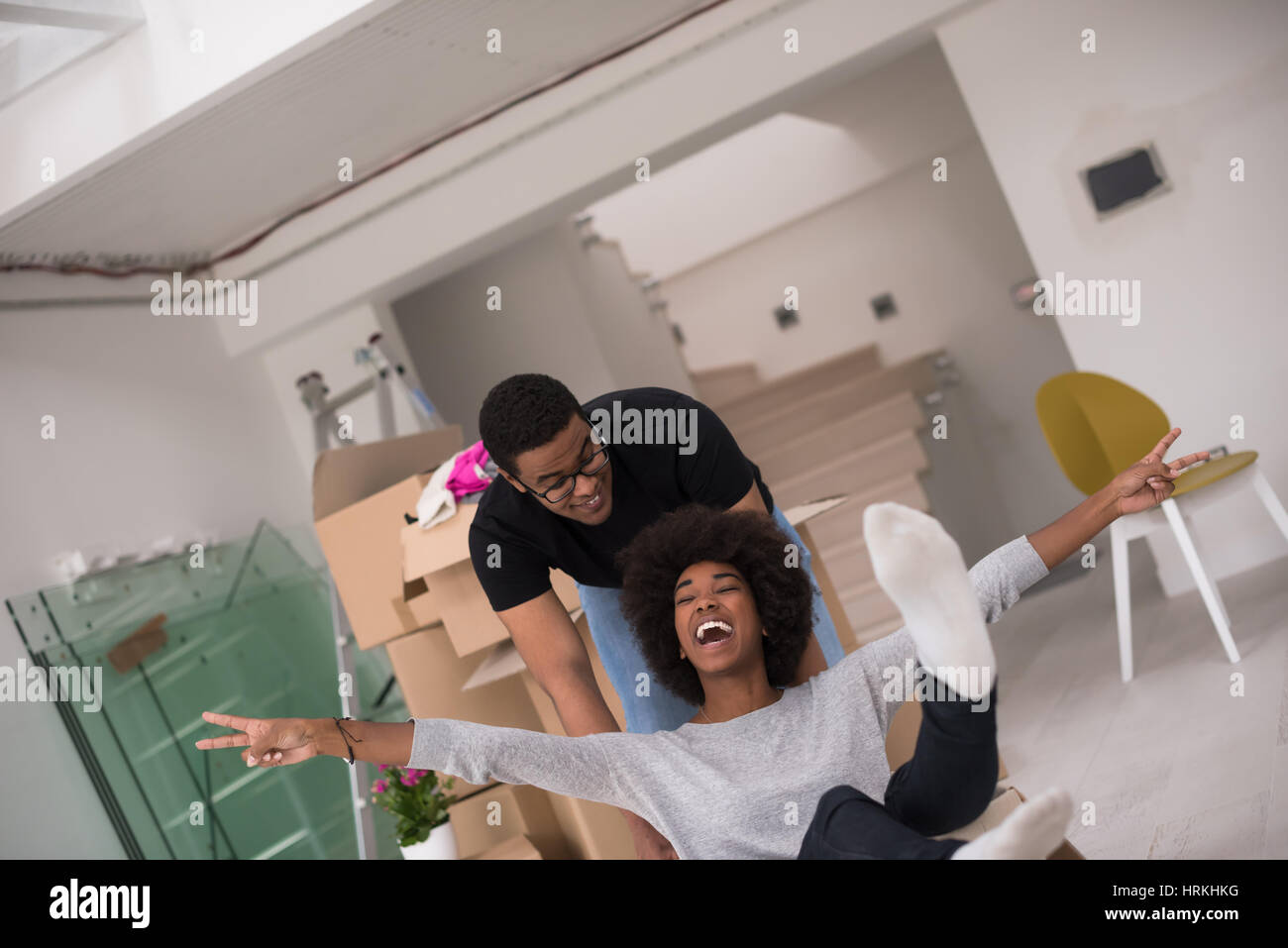 African American couple sitting in a box playing with packing material ...