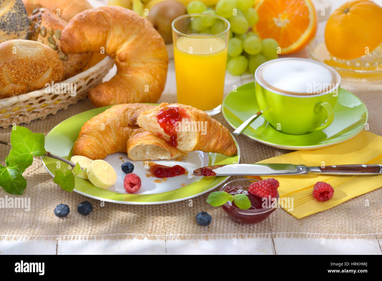 Breakfast table with a cup of cappuccino and fresh croissants with ...