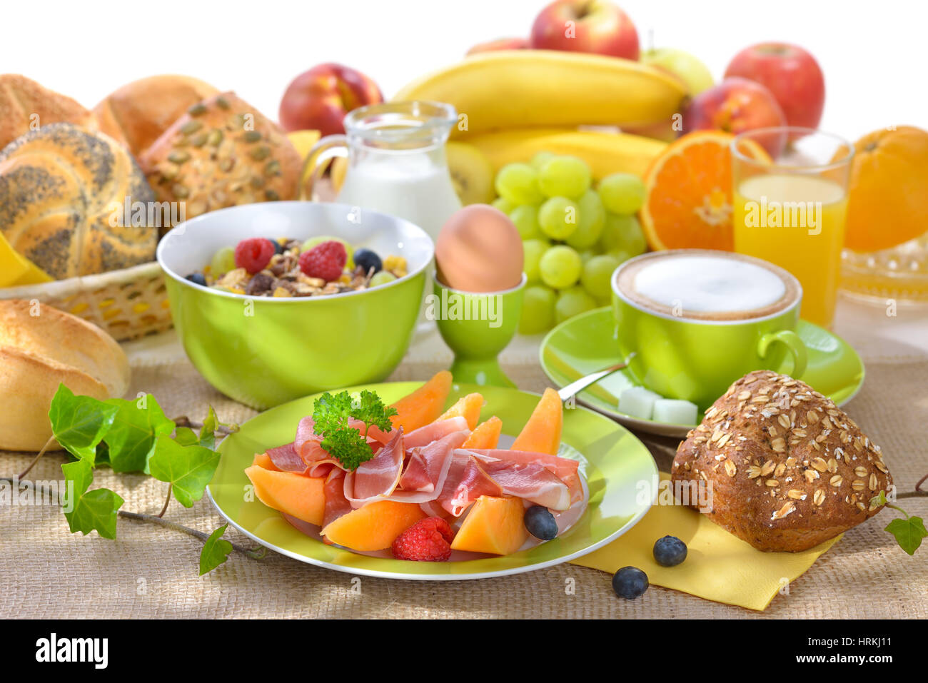 Laid breakfast table with melon and ham against a white background ...