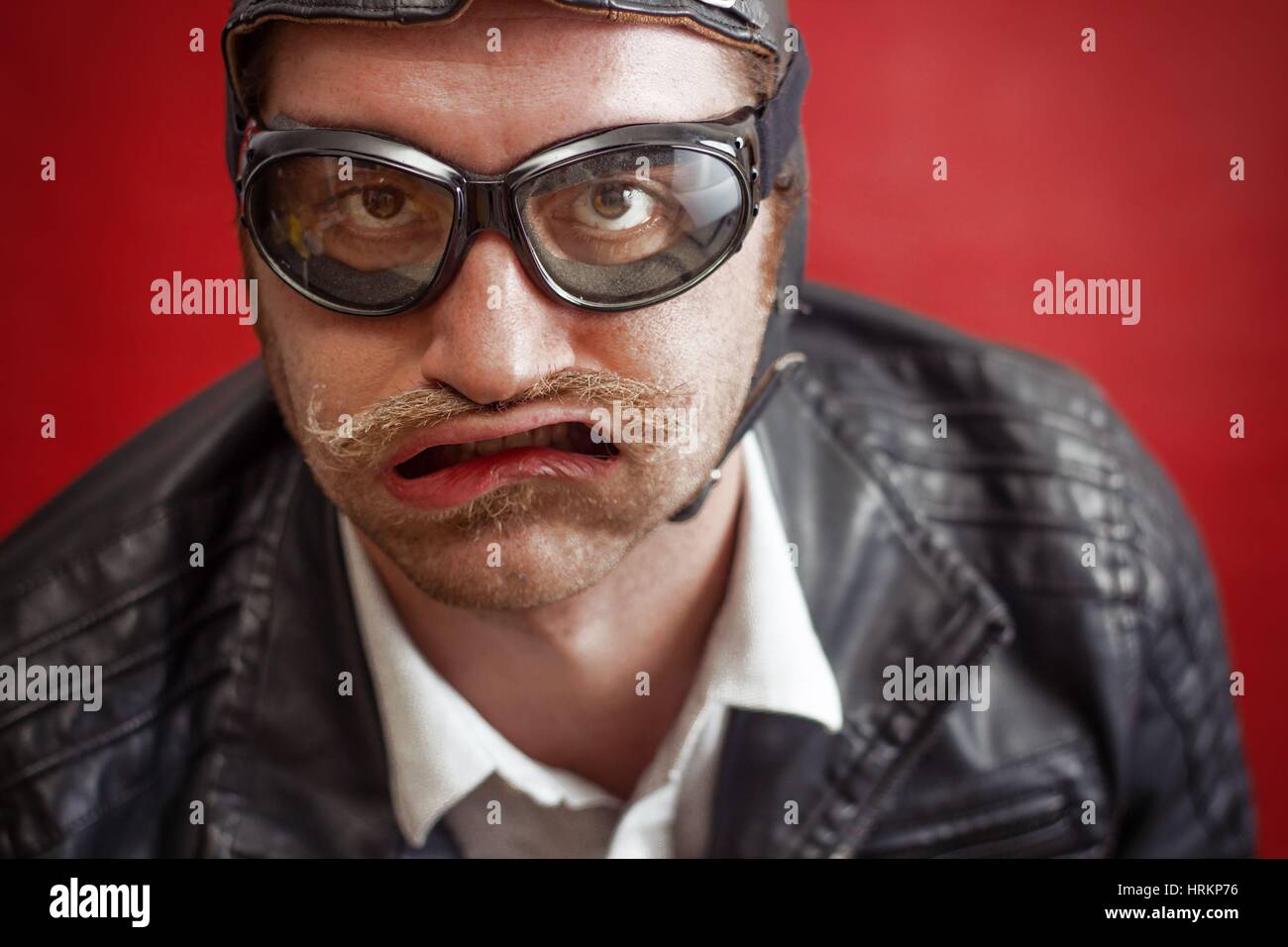 Man wearing aviator hat and goggles makes silly facial expression from ...