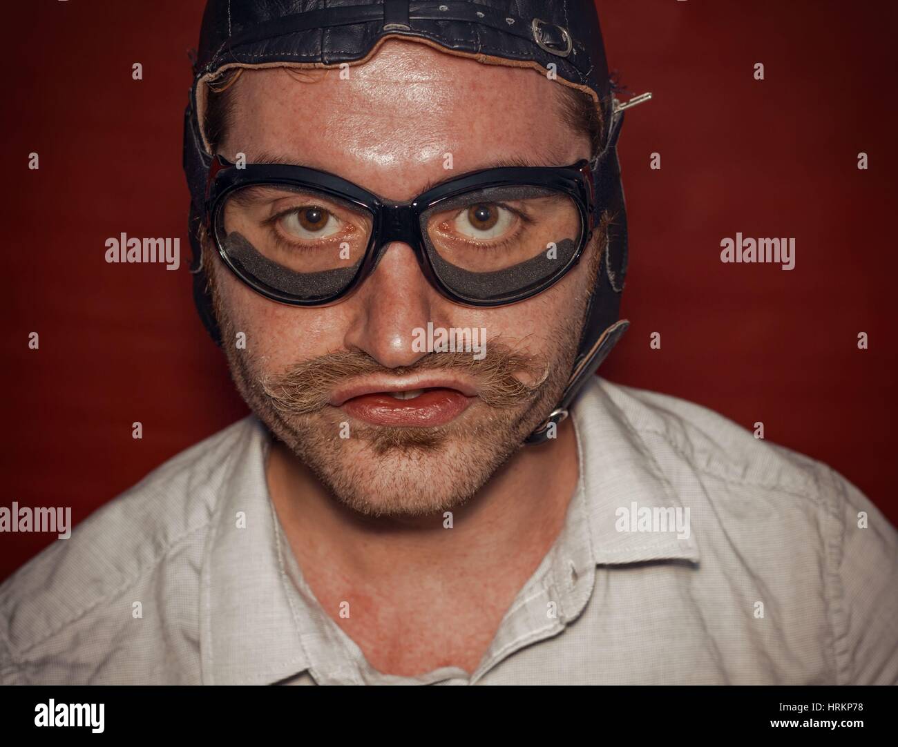 Man wearing aviator hat and goggles makes silly facial expression from ...