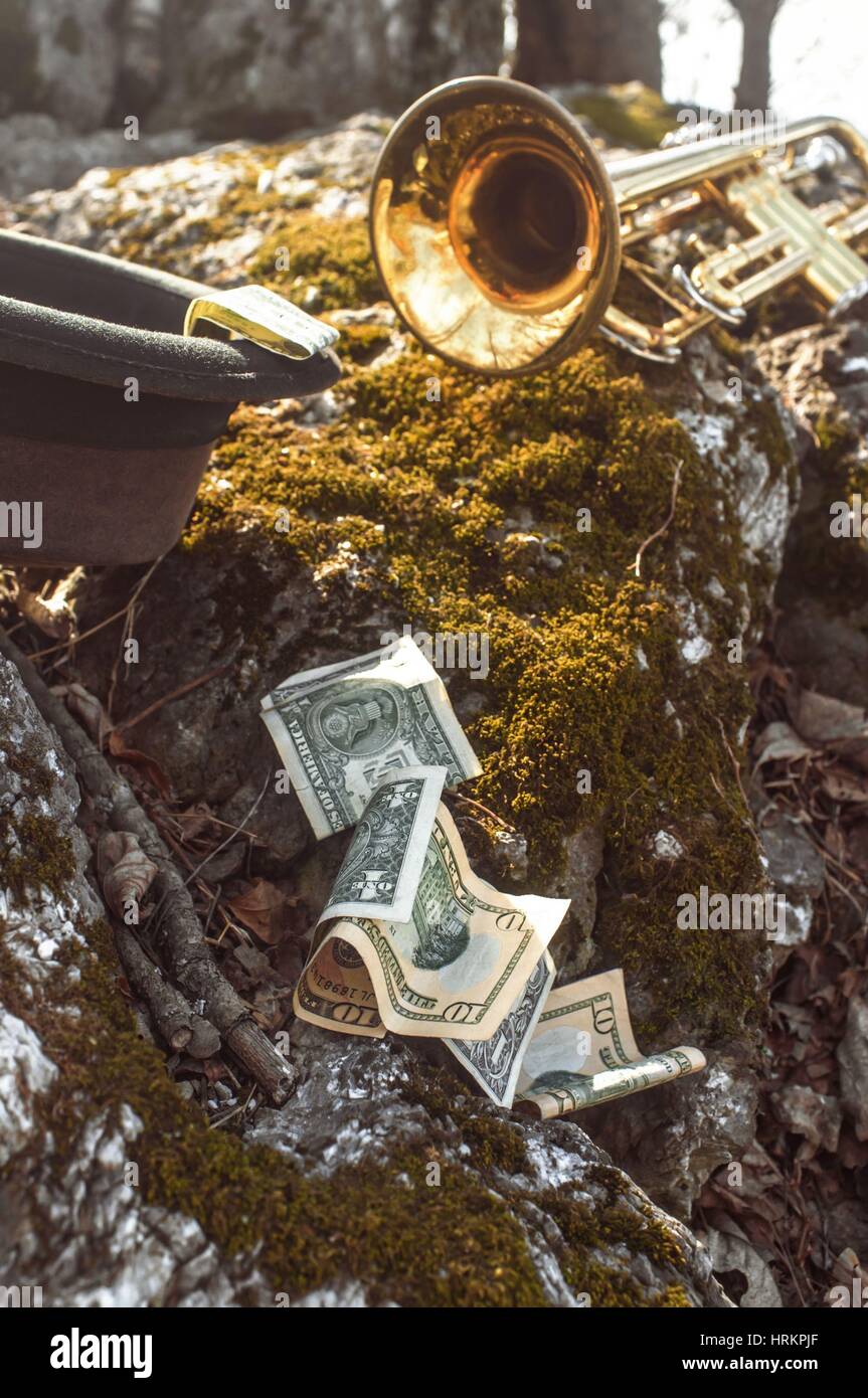 Old worn trumpet next to money collecting hat on mossy rocks Stock ...