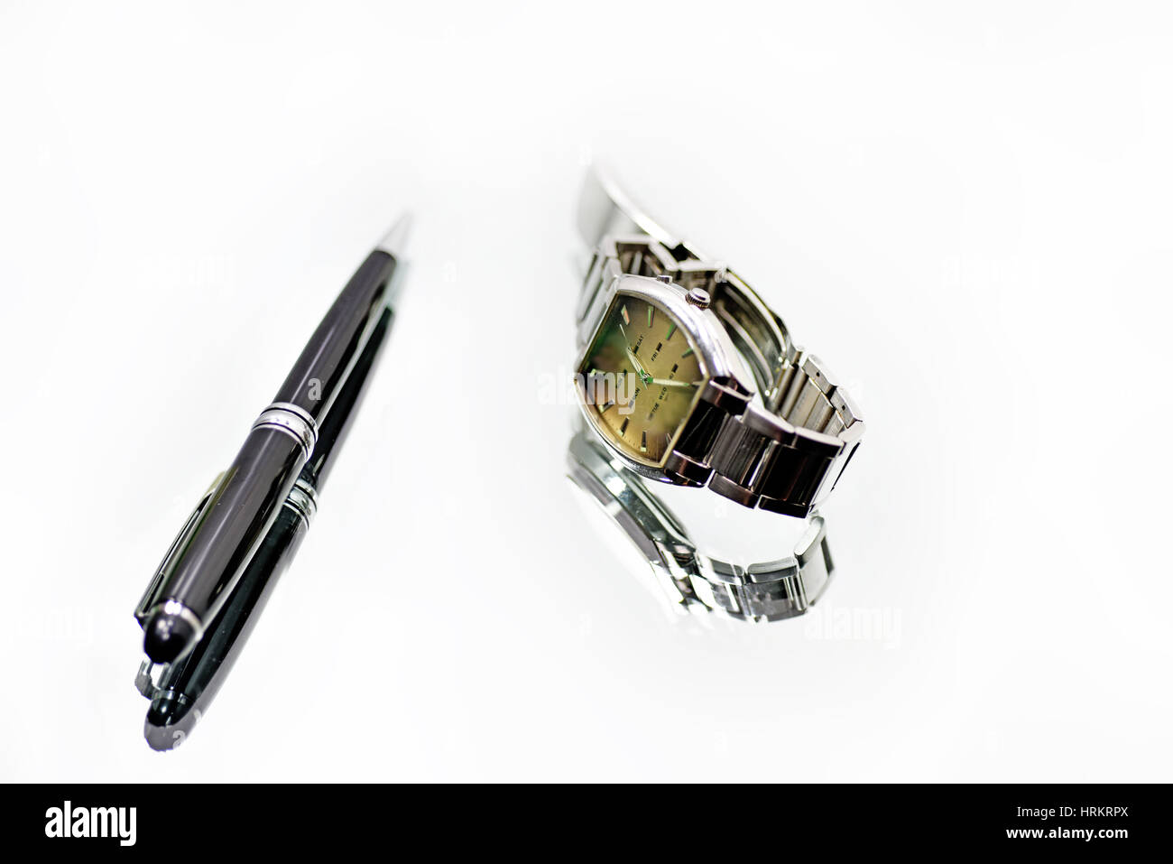 Clock and pen on mirror with reflection. Isolated on white background ...