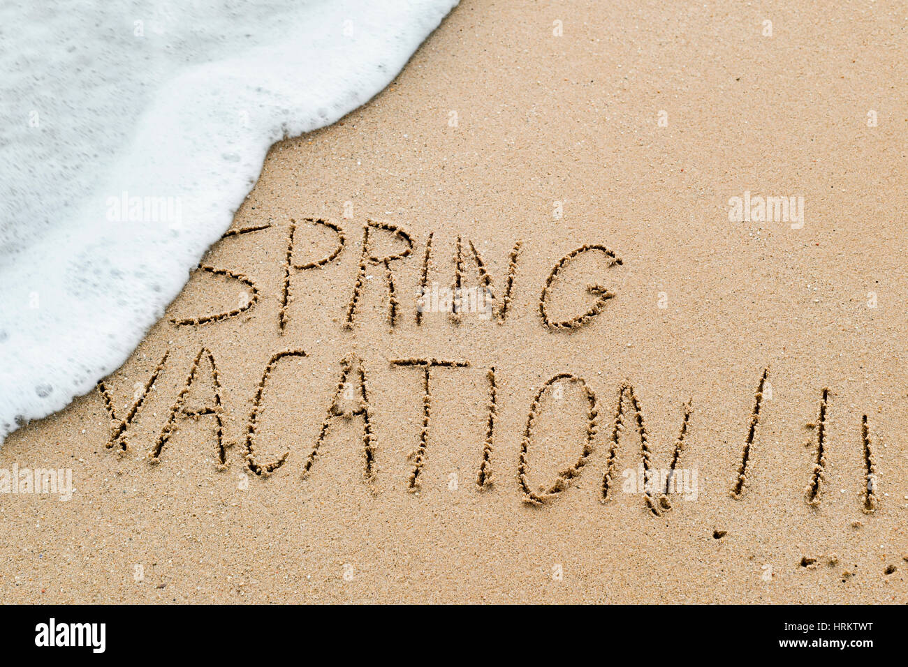 closeup of the text spring vacation written in the sand of a beach ...