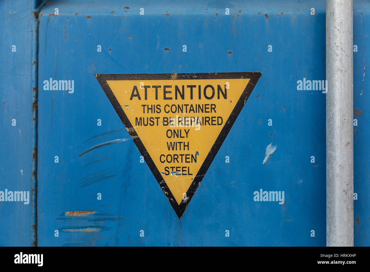 Attention yellow triangle sign on blue container Stock Photo - Alamy