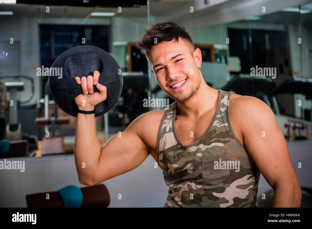 Attractive young athletic man exercising in gym, working out using ...