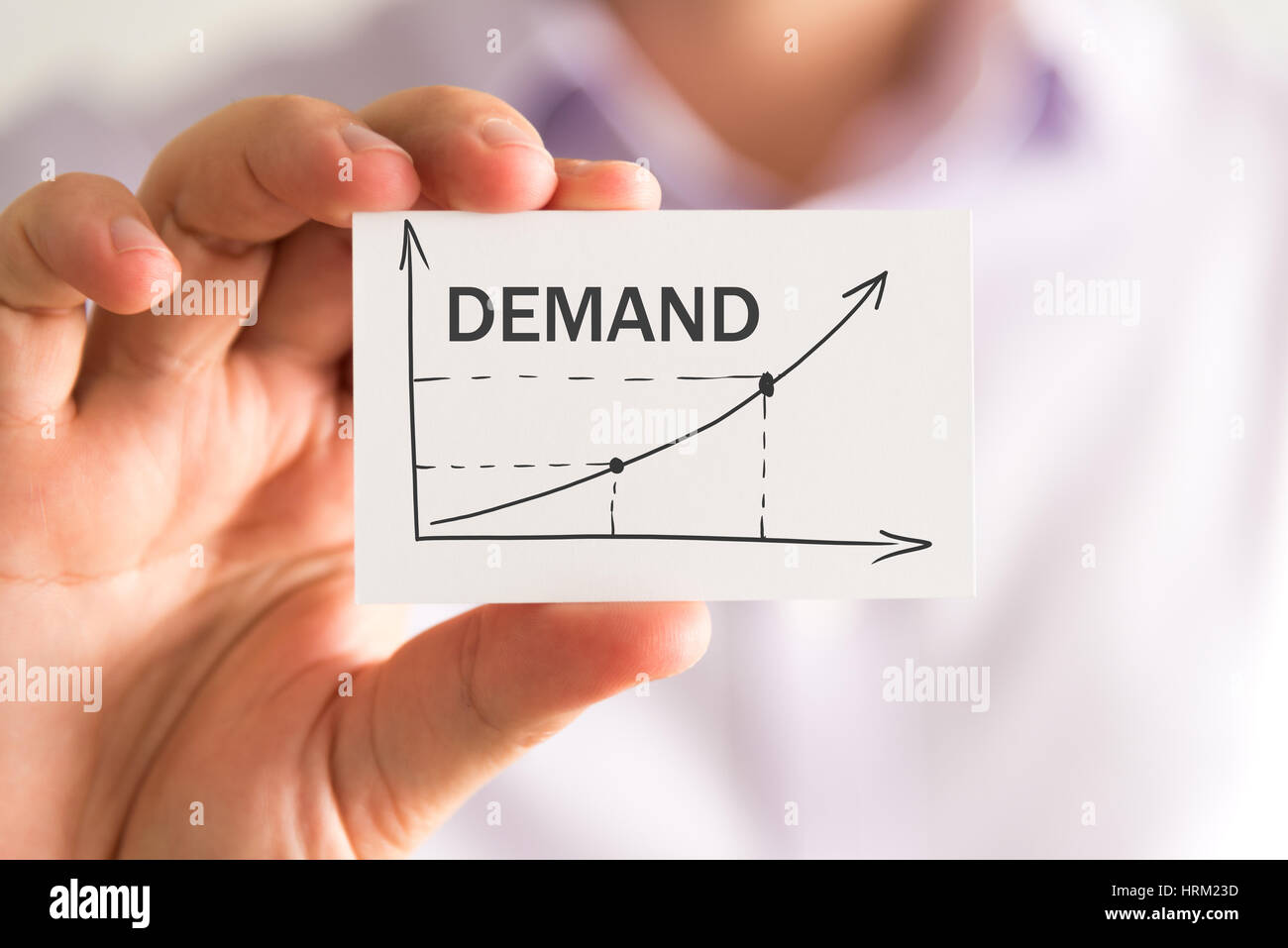 Closeup on businessman holding a card with DEMAND rising arrow and ...