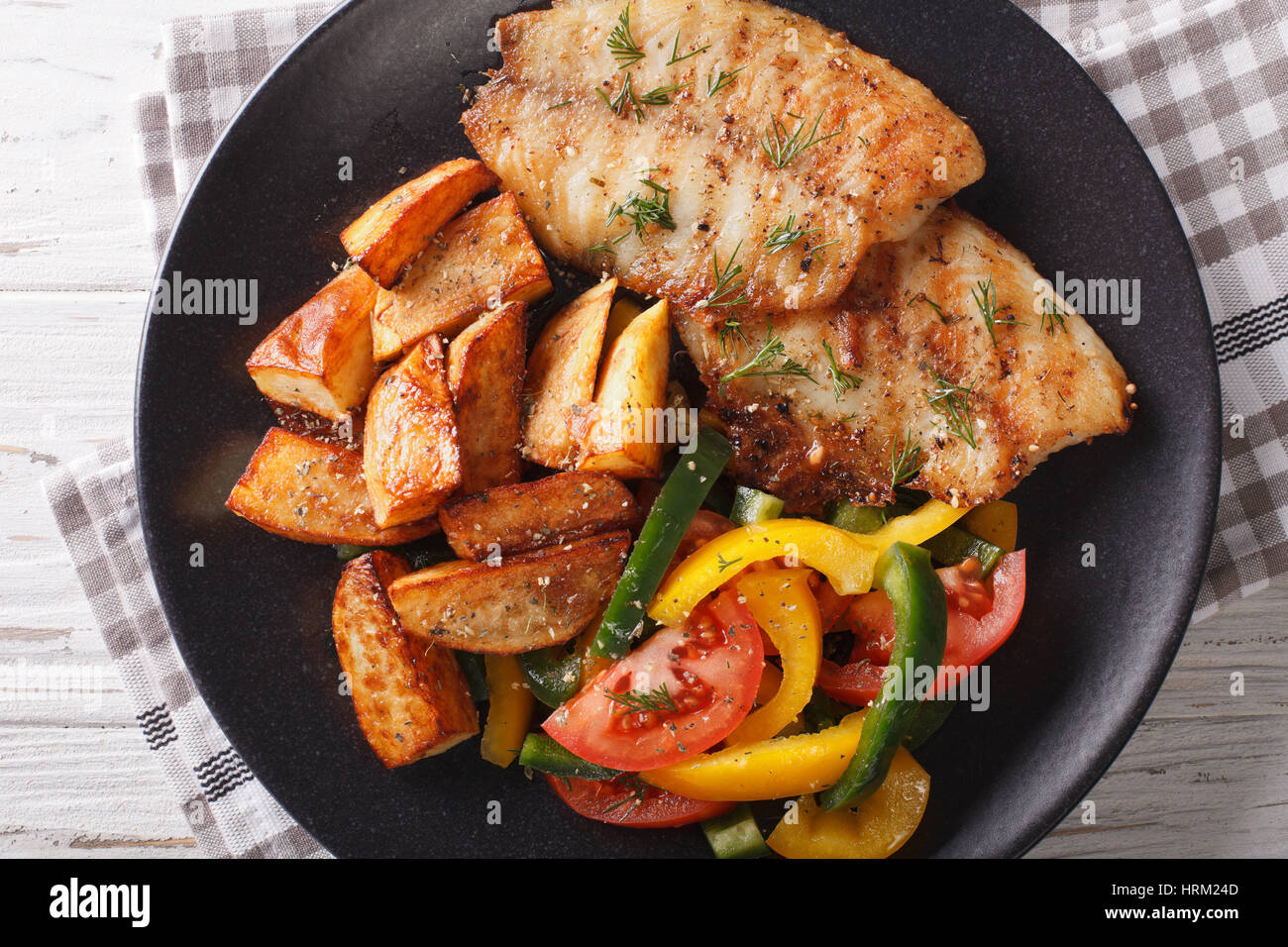 White fish fillet and potato wedges, fresh salad on a plate close-up ...