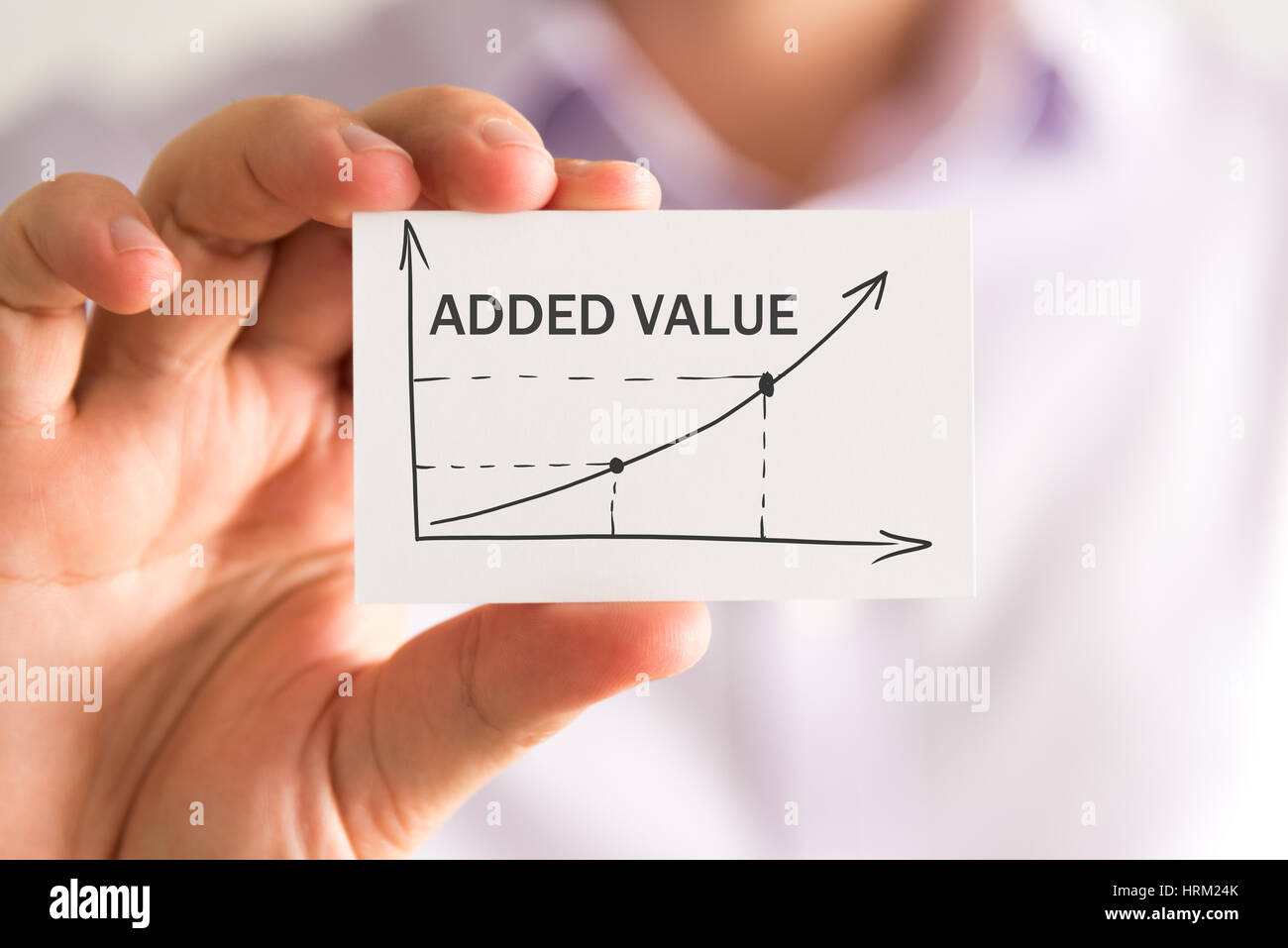 Closeup on businessman holding a card with ADDED VALUE rising arrow and ...