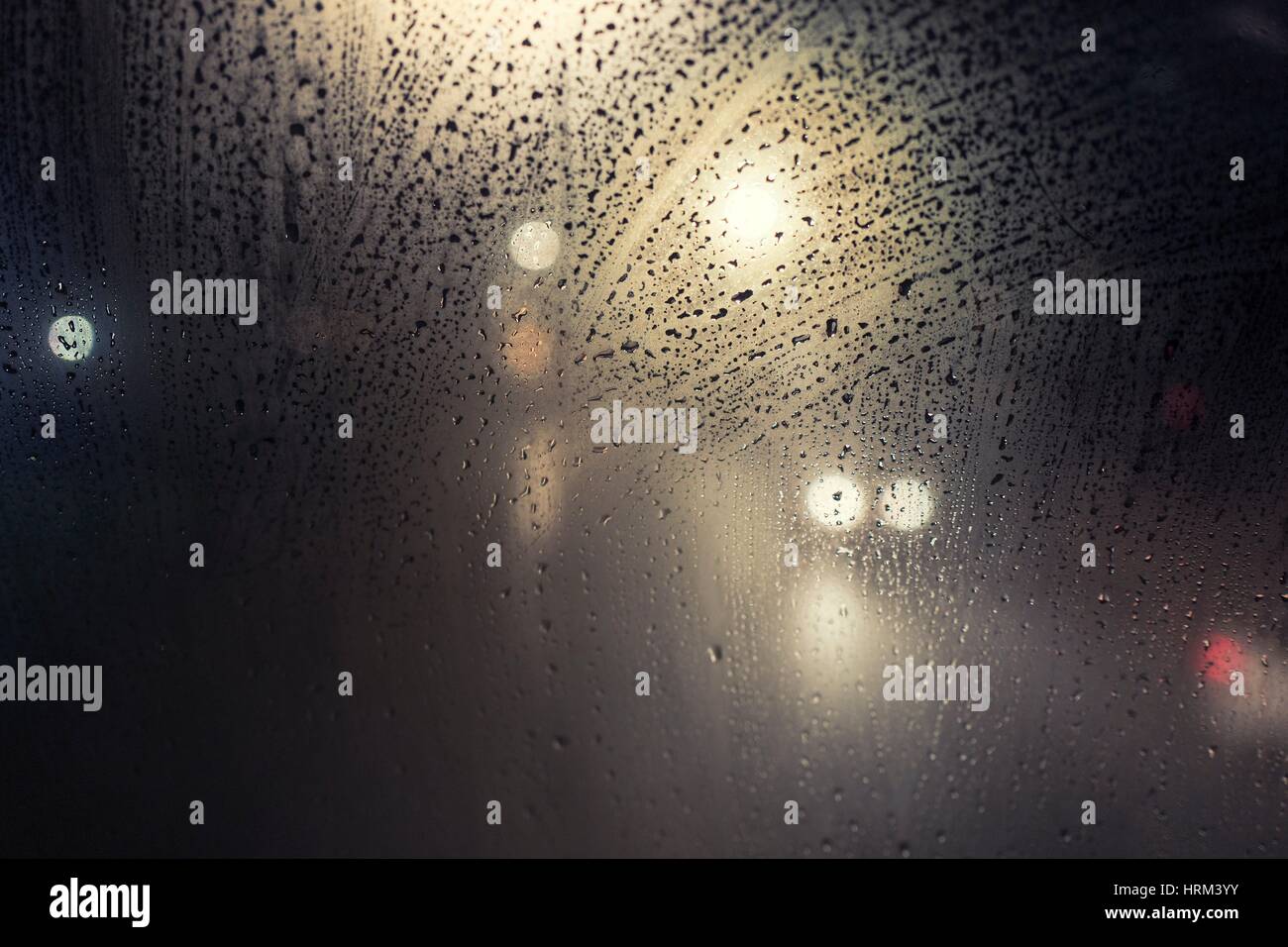 Bus window with water drops and light reflections on a rainy day ...