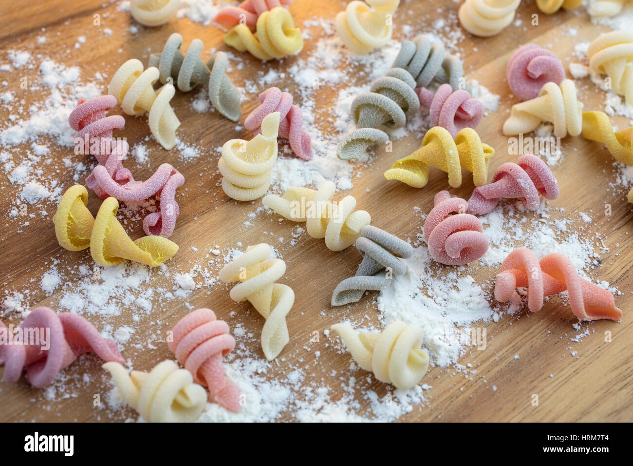 Curly and twisted pasta shapes on a cutting board in various colors of ...