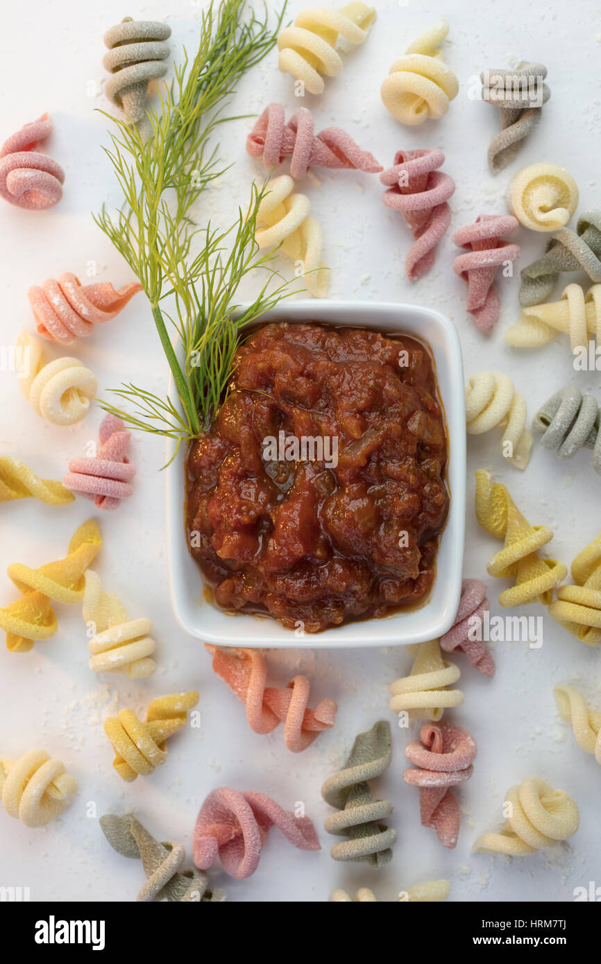 Curly and twisted pasta shapes on a cutting board in various colors of ...