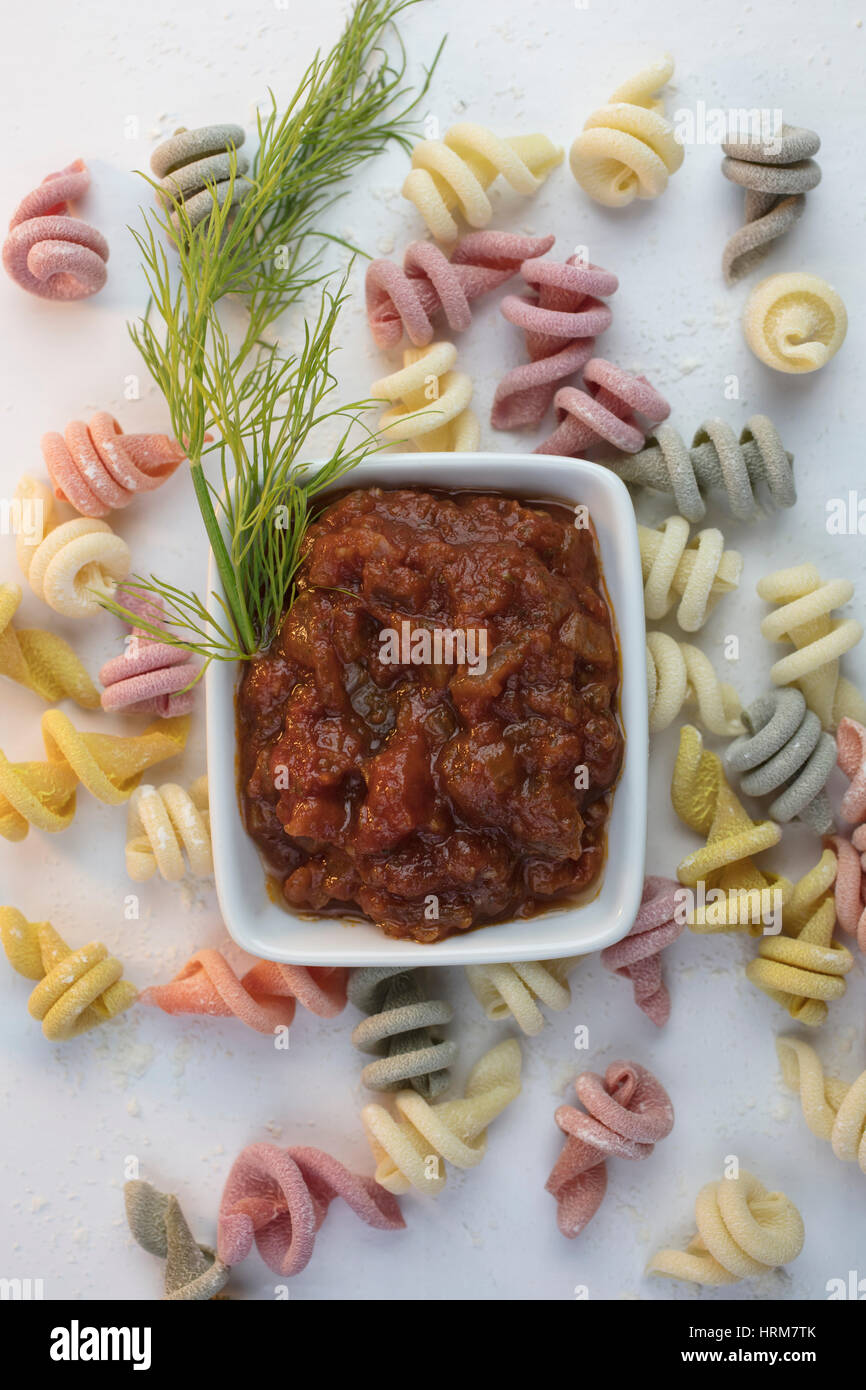 Curly and twisted pasta shapes on a cutting board in various colors of ...