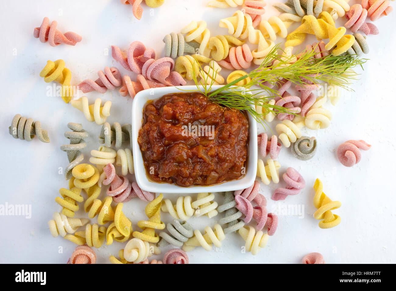 Curly and twisted pasta shapes on a cutting board in various colors of ...