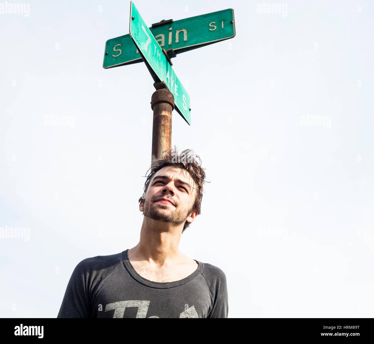 A young man leaning against a street sign pole looking upward Stock ...