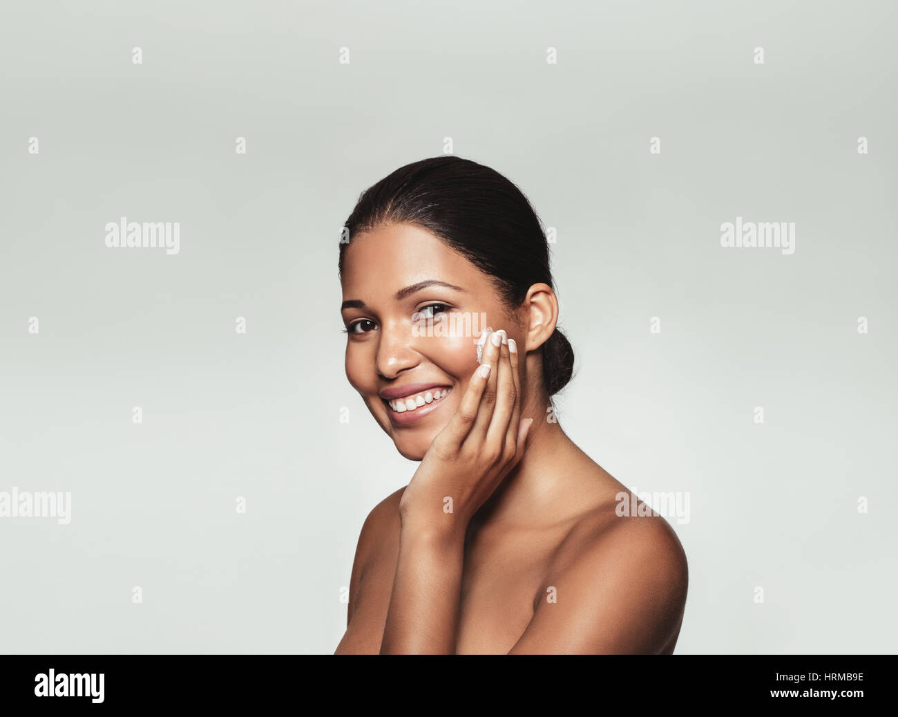 Portrait of beautiful female model applying face cream. Close up of ...