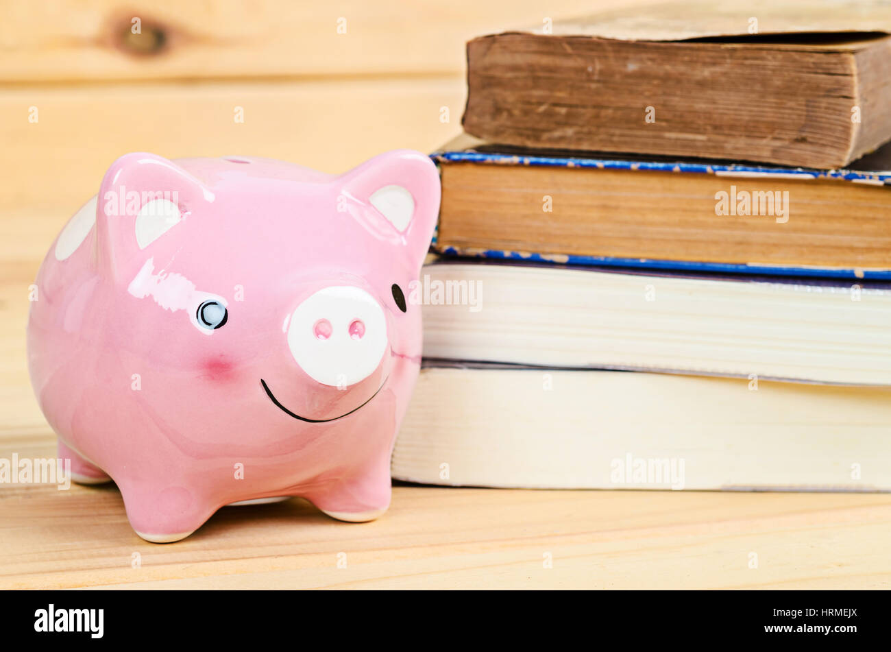 Pink Piggy bank and books on wood background as concept image of the ...