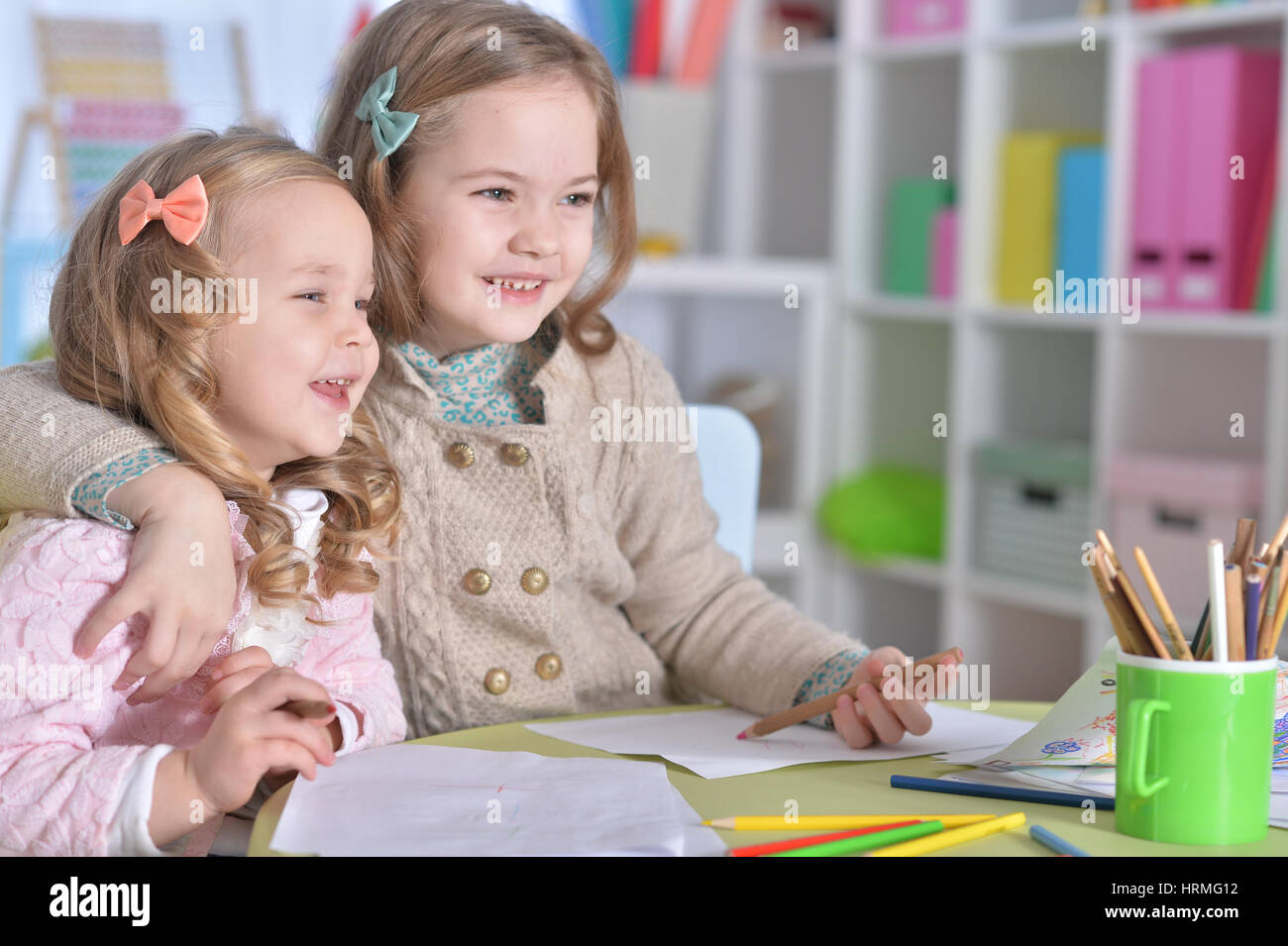 Two cute little girls drawing with pencils Stock Photo - Alamy
